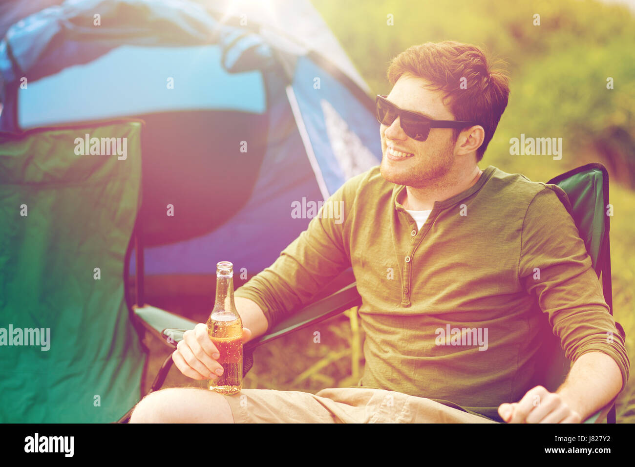 happy young man drinking beer at campsite tent Stock Photo - Alamy