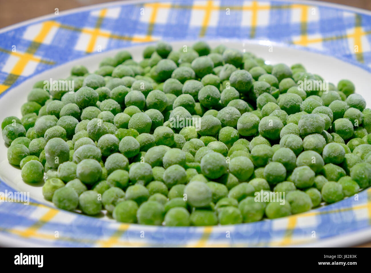 Frozen peas petit pois on a white plate Stock Photo - Alamy