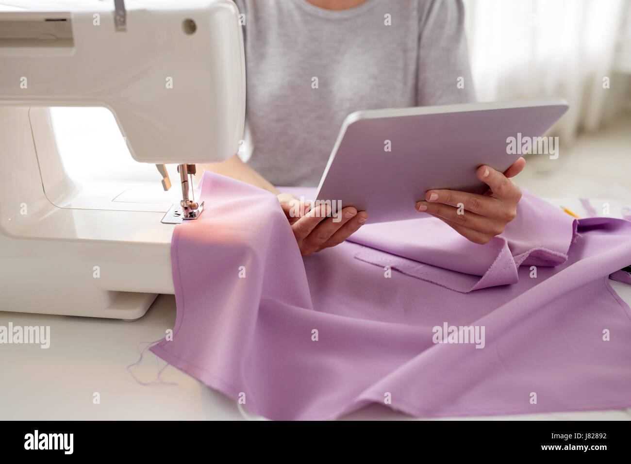 tailor with sewing machine, tablet pc and fabric Stock Photo - Alamy