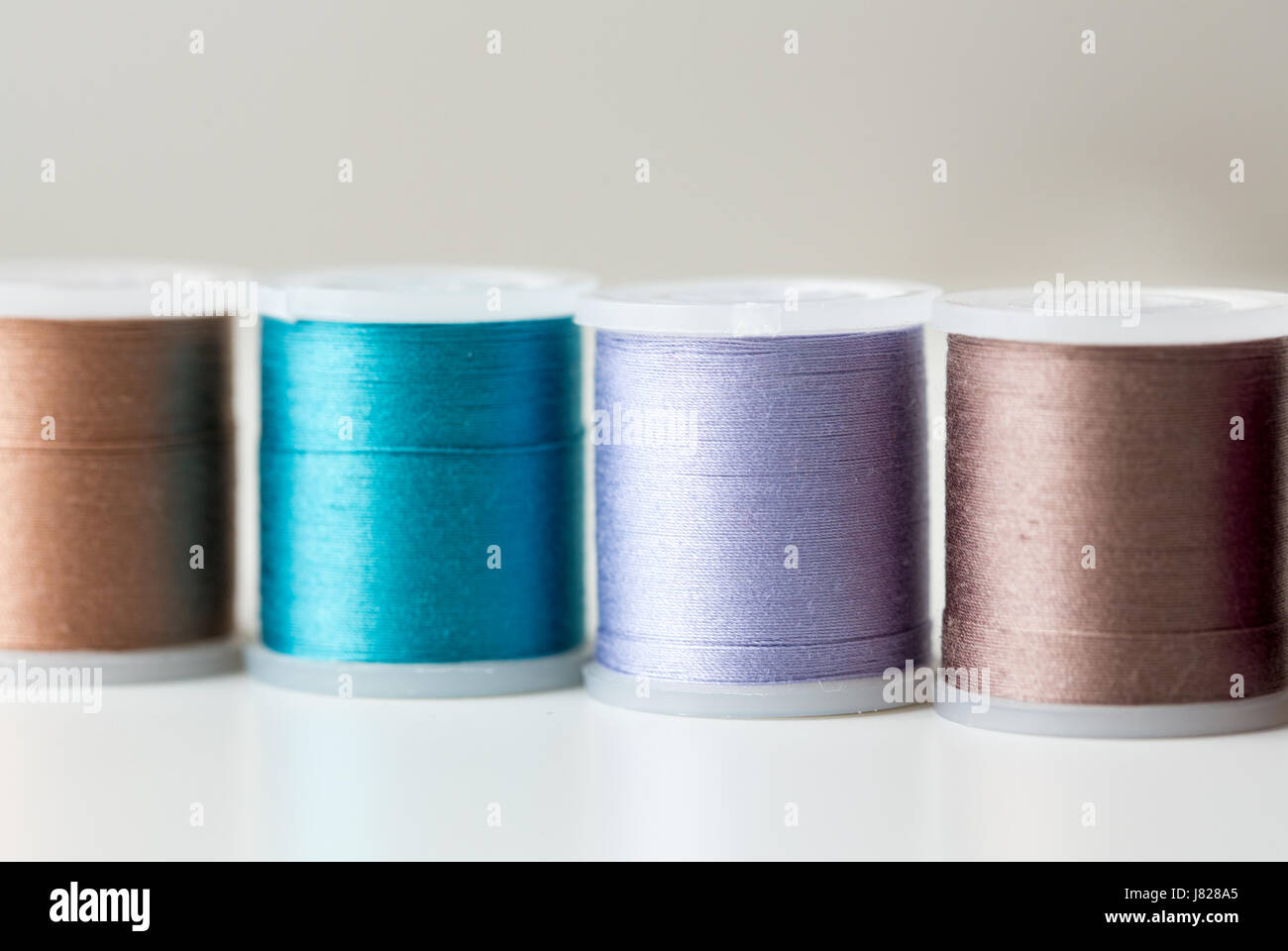 row of colorful thread spools on table Stock Photo - Alamy