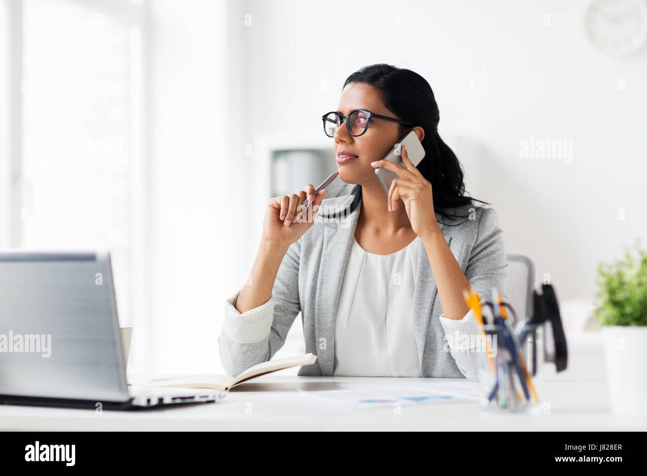 businesswoman calling on smartphone at office Stock Photo - Alamy