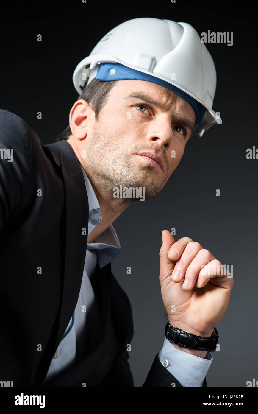 Thoughtful professional male engineer in suit and helmet Stock Photo ...