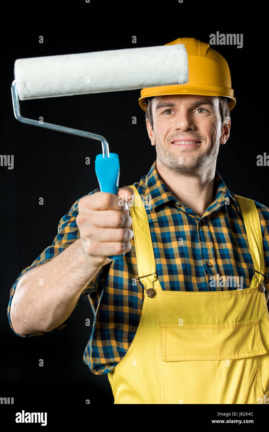 Male worker holding paint roller and smiling on black Stock Photo - Alamy