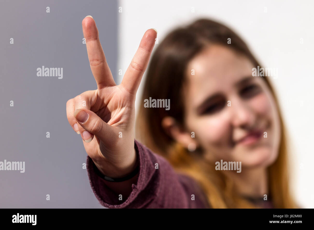 Young woman showing the sign of victory or peace Stock Photo - Alamy