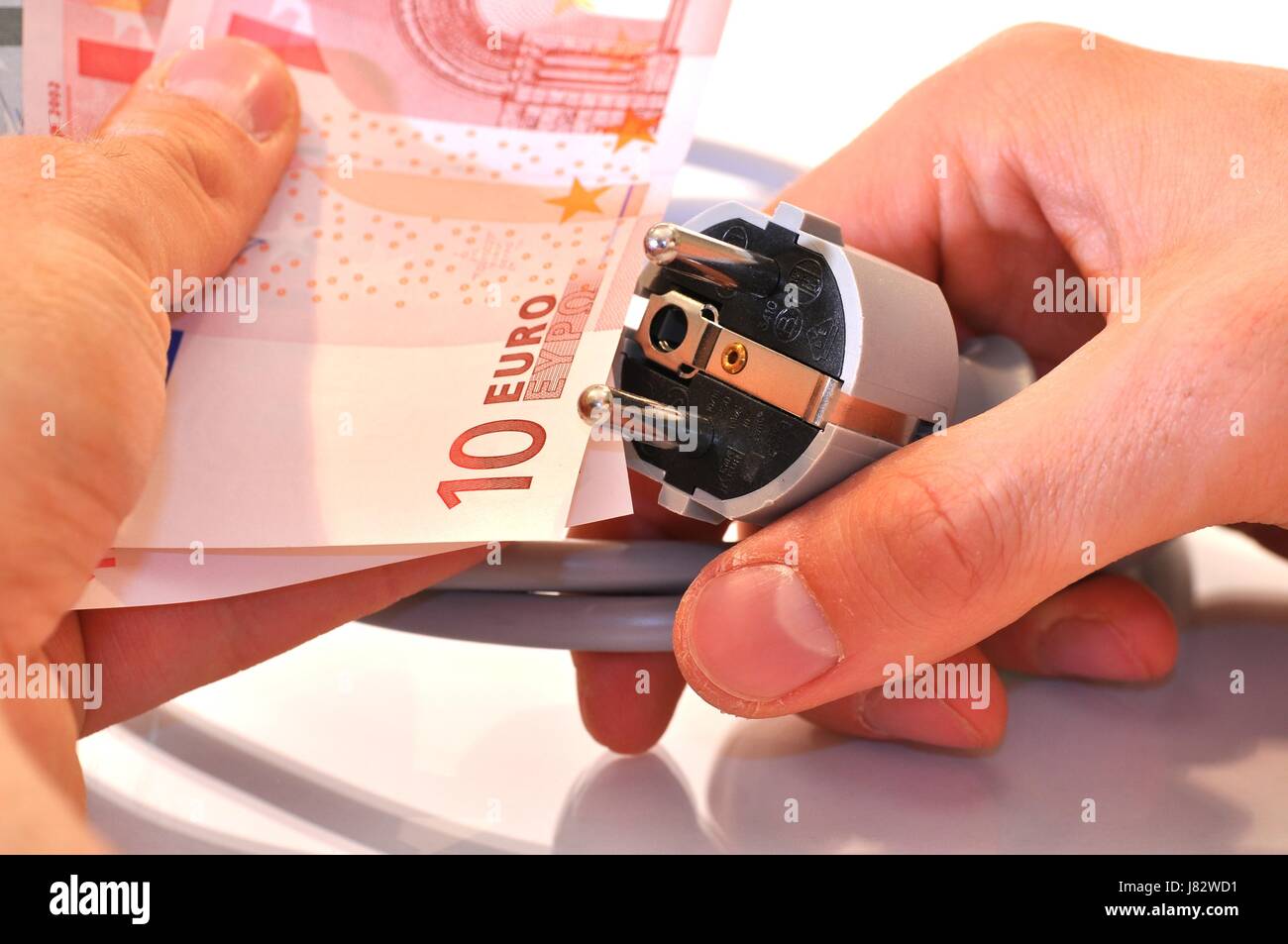 power plug and money bills in hand Stock Photo - Alamy