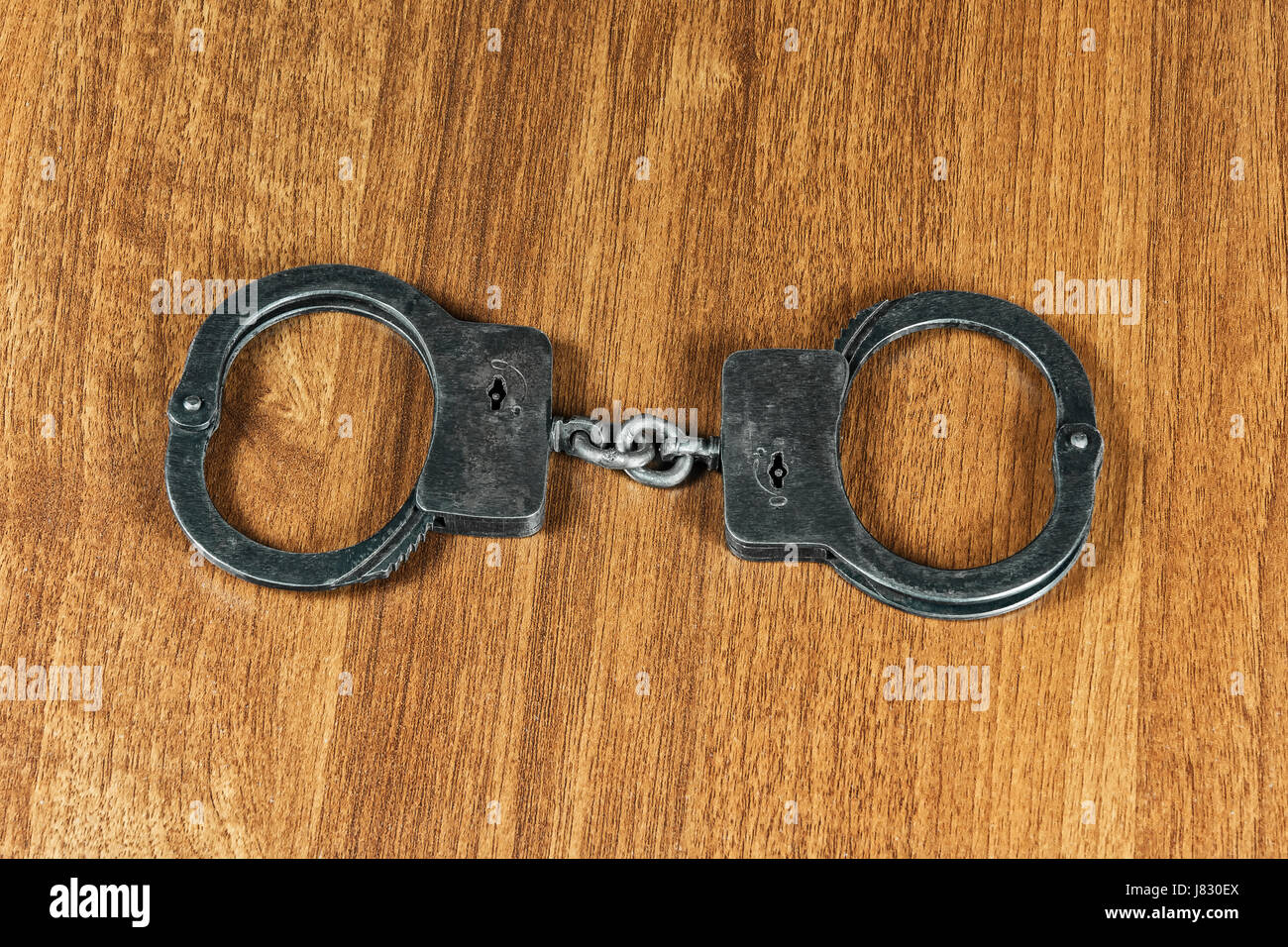 On the wooden table lie the police handcuffs Stock Photo - Alamy