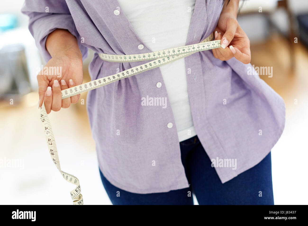Woman holding tape measure around her waist Stock Photo - Alamy