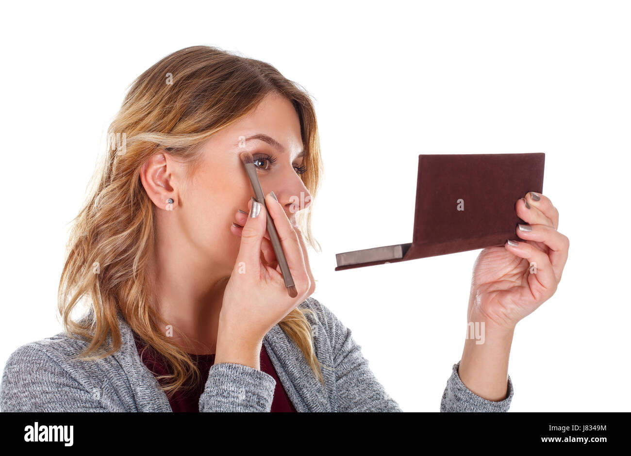 Picture of a pretty young lady while doing her make-up Stock Photo - Alamy