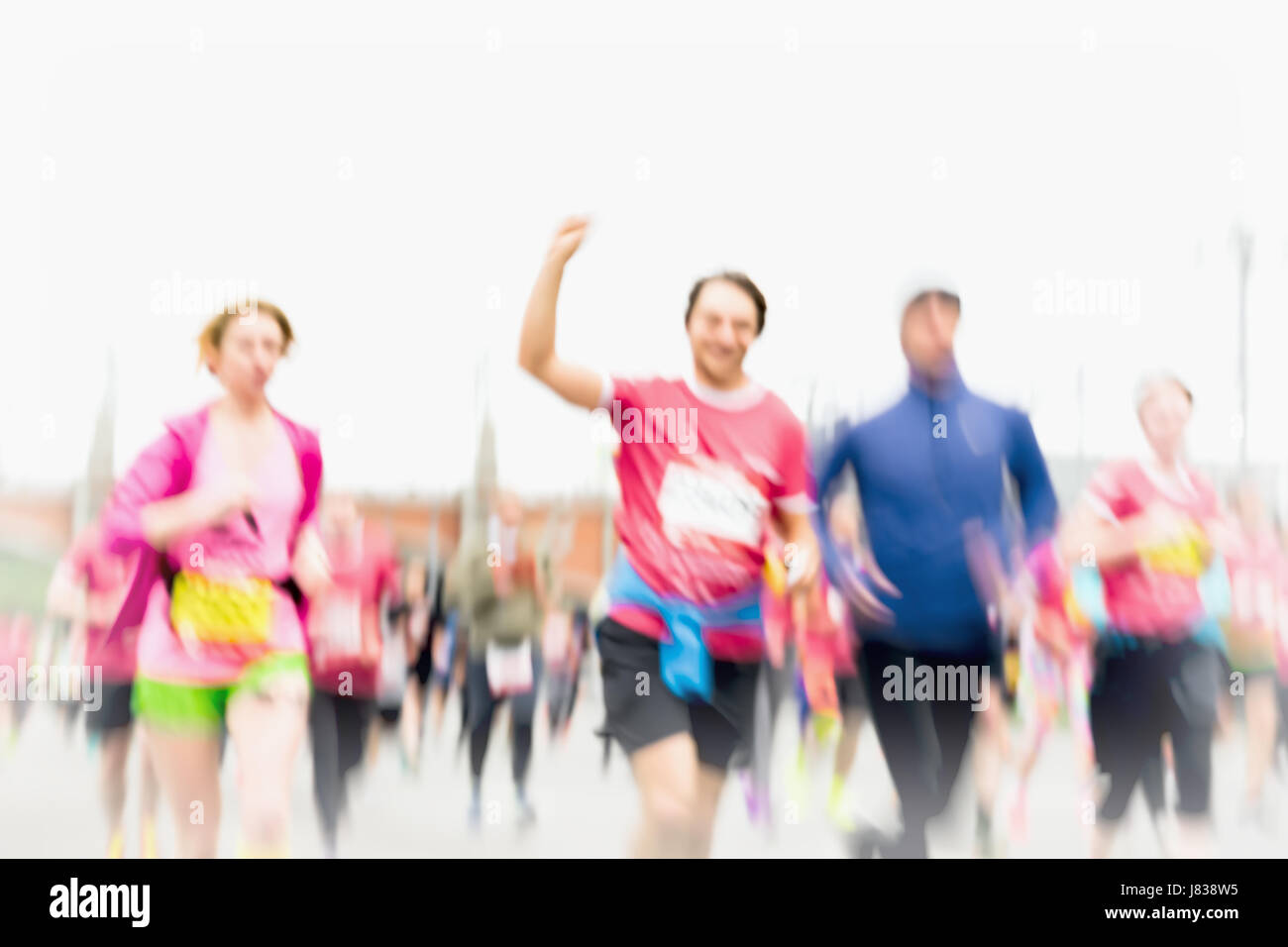 Happy man winning race in group of sportsmen running marathon and ...