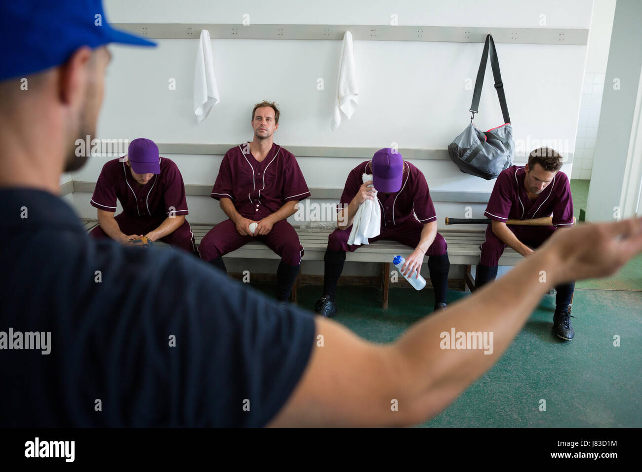 Rear view of coach discussing with baseball team at locker room Stock ...