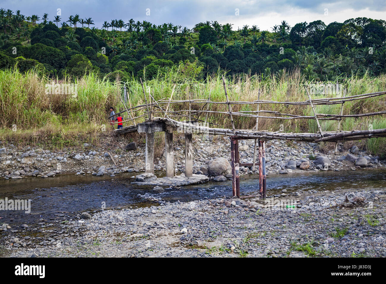 Indigenous Filipino Aeta woman and child cross a bamboo footbridge In the mountains behind Subic ...