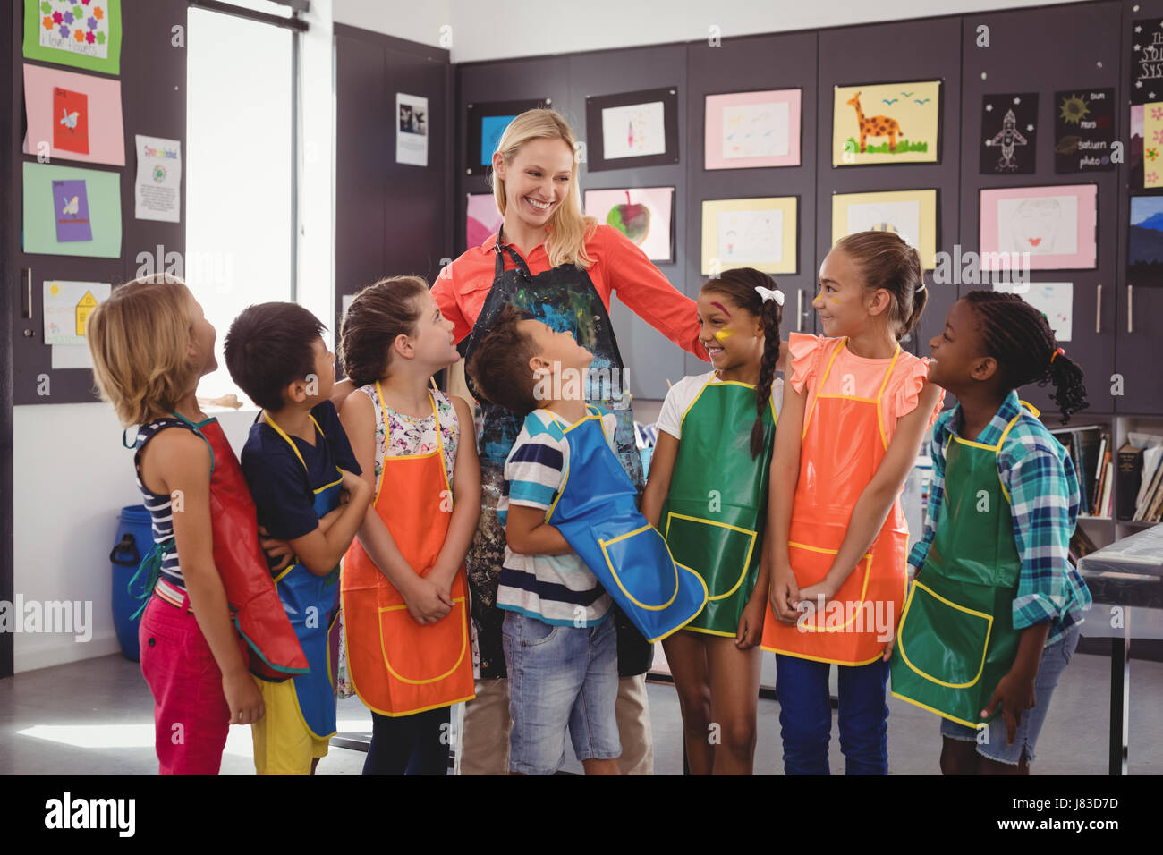 Teacher and schoolkids interacting with each other in drawing class ...