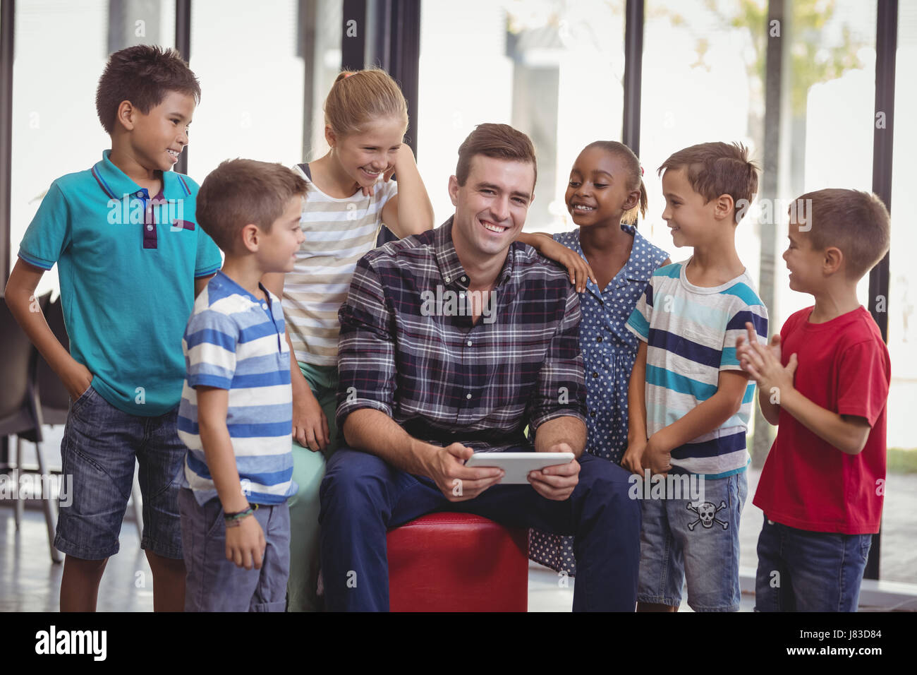 Happy teacher and schoolkids using digital tablet in library at school ...