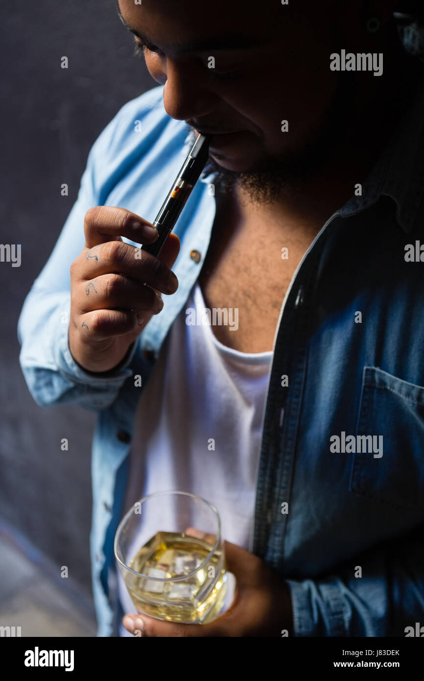 Man smoking while having whisky at the entrance of bar Stock Photo - Alamy