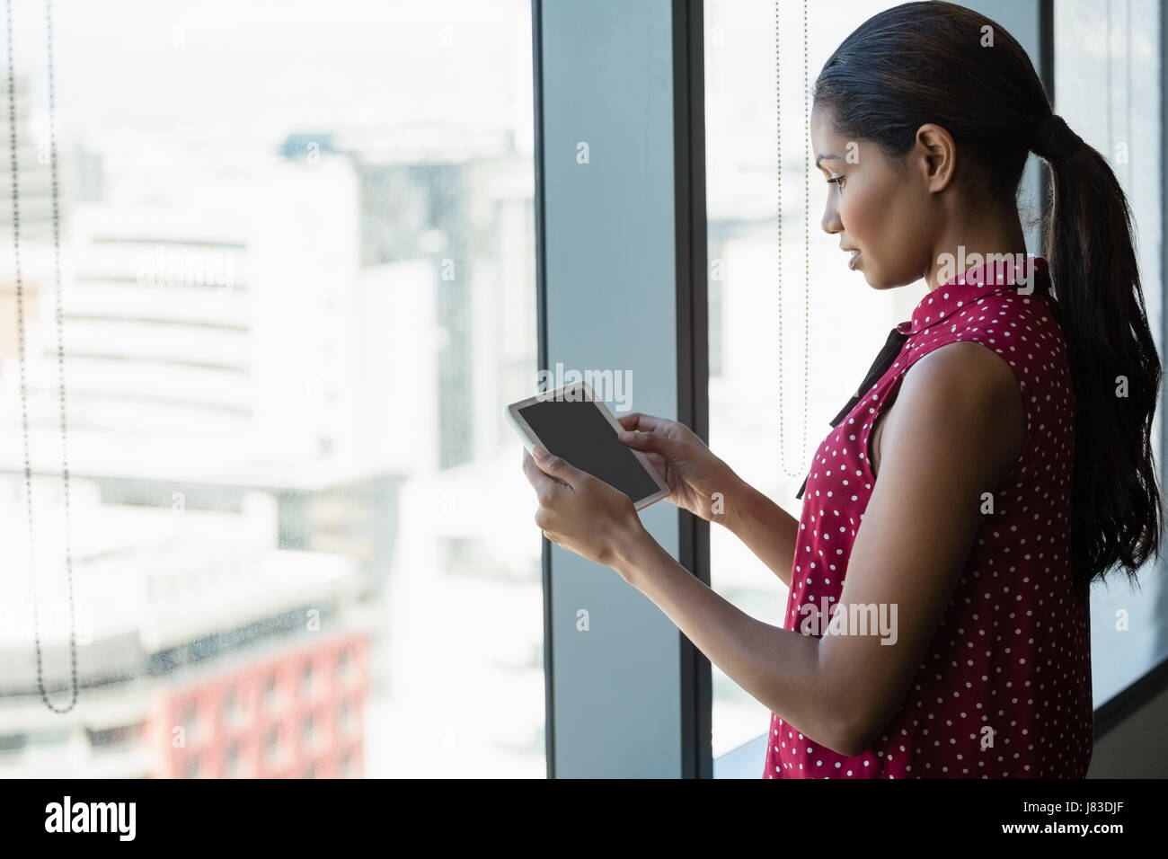 Executive using digital tablet near window in office Stock Photo - Alamy