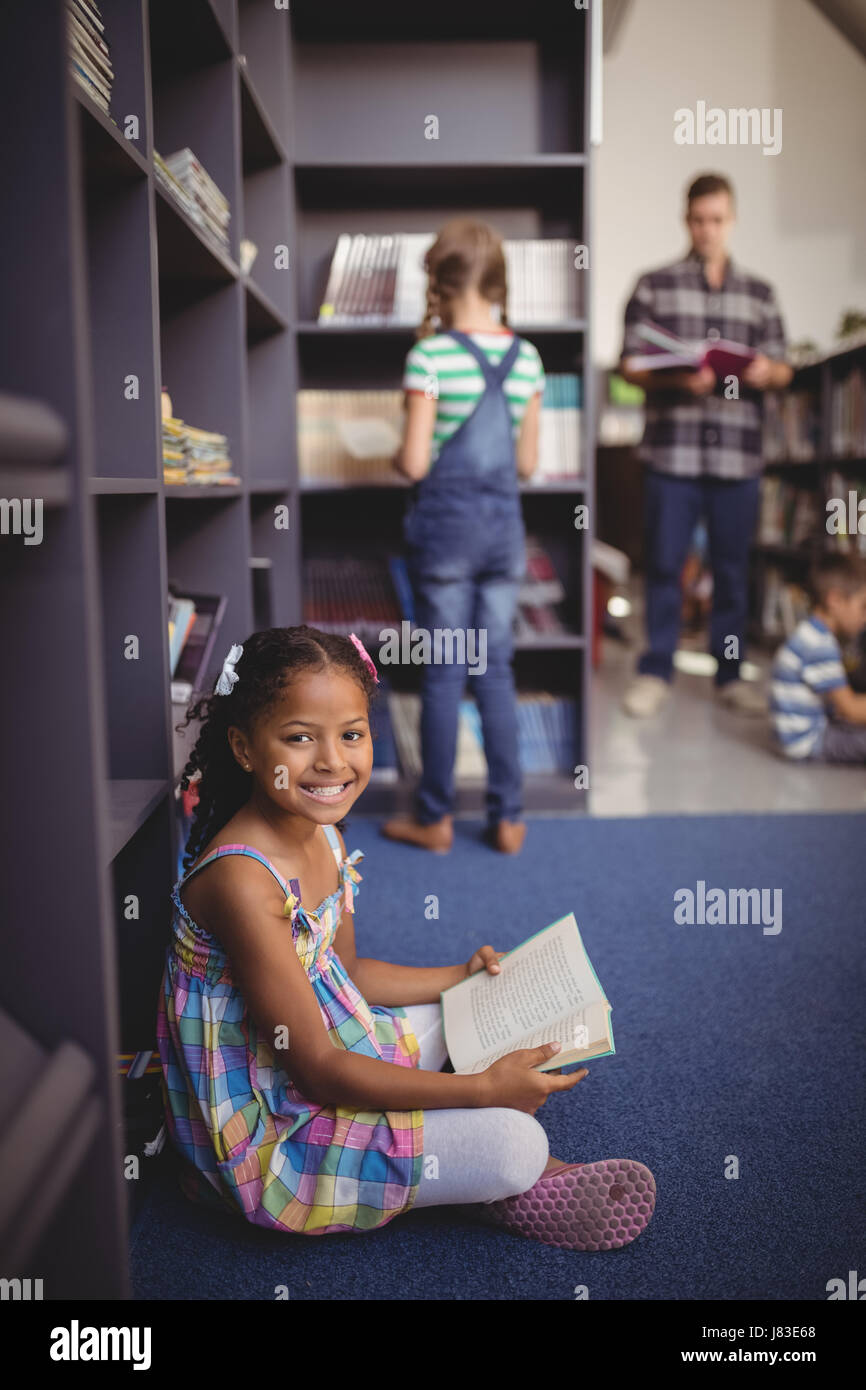 Portrait smiling schoolgirl reading book in library at school Stock ...