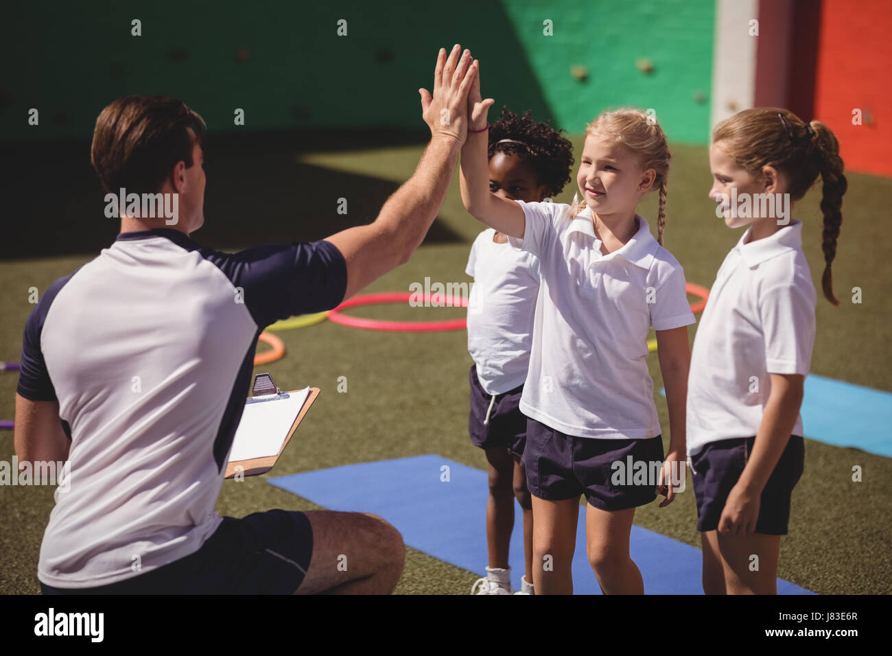 Coach and schoolkids giving high five to each other in schoolyard Stock ...