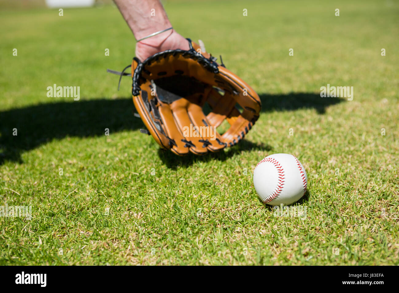 Cropped hand of baseball pitcher by ball on playing field Stock Photo ...