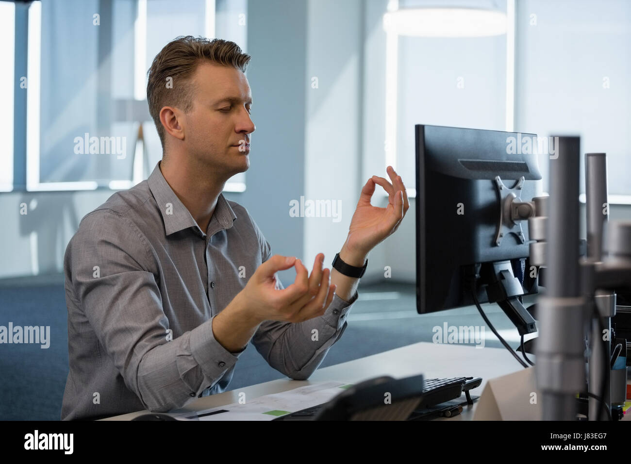 Executive meditating at desk in office Stock Photo - Alamy