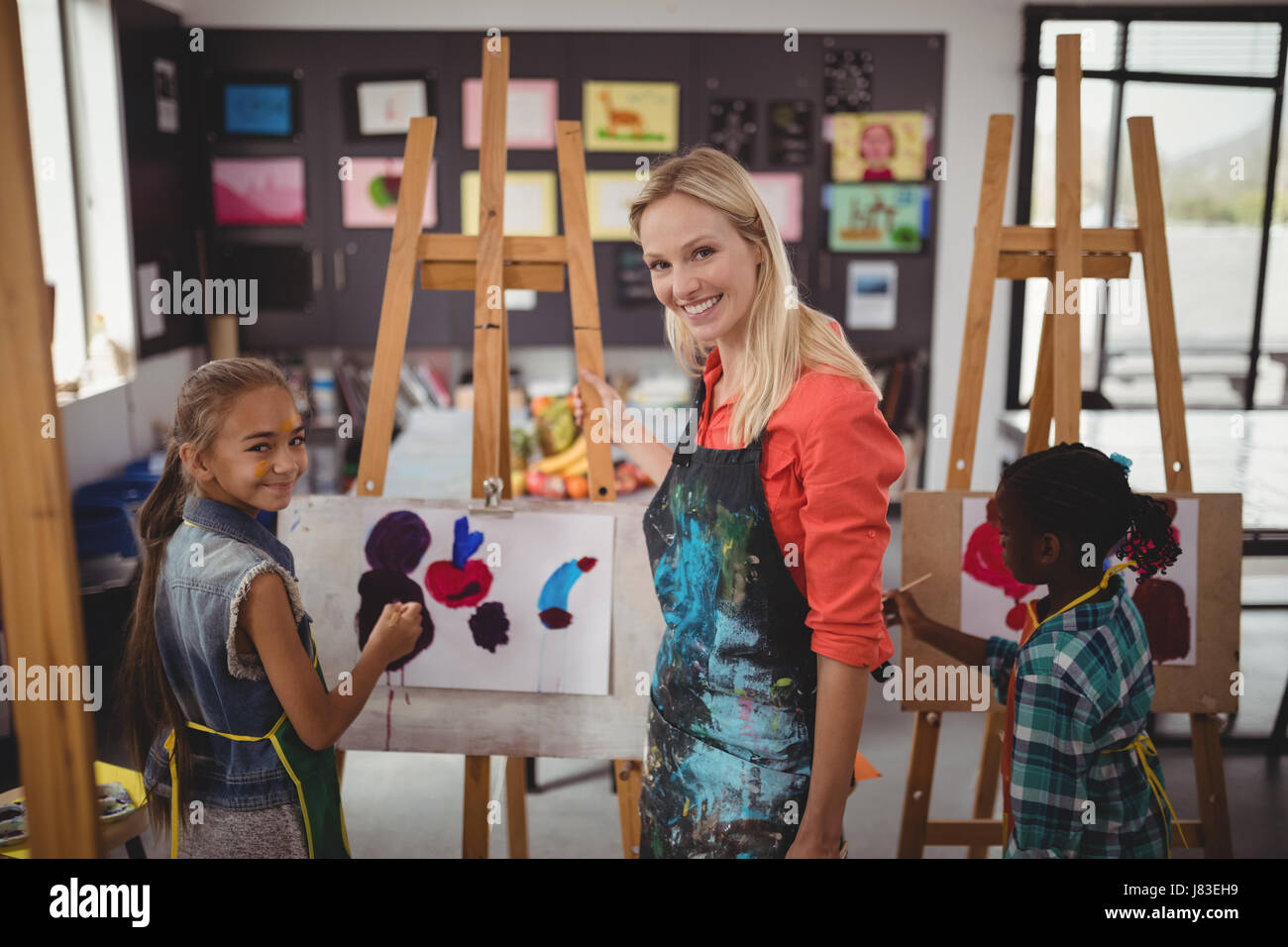 Teacher assisting schoolkid in drawing class at school Stock Photo - Alamy