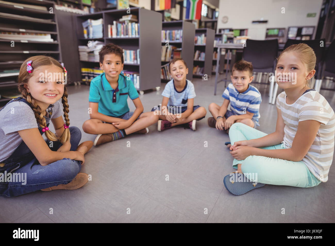 Portrait of happy schoolkids sitting in library at school Stock Photo ...