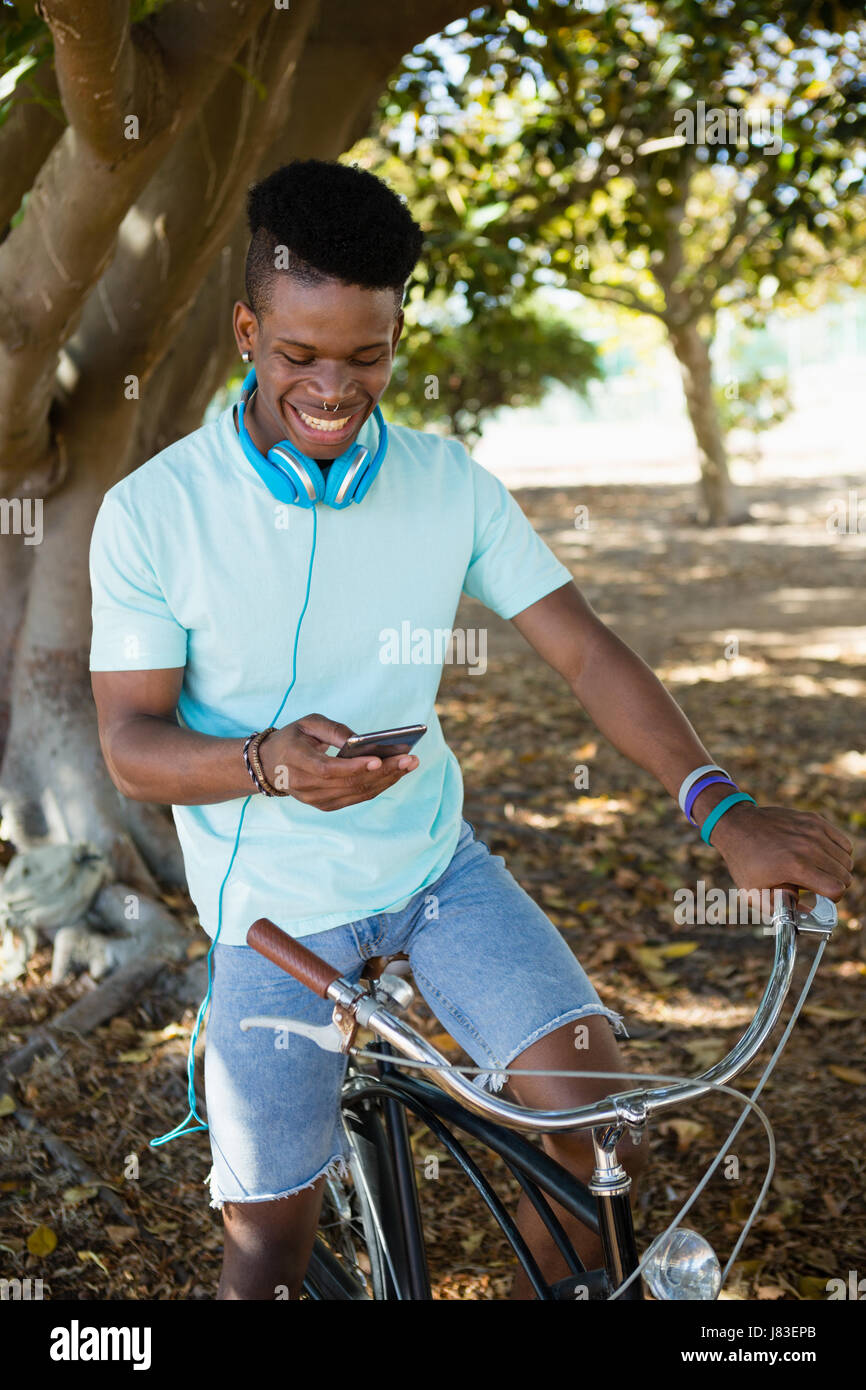 Man using mobile phone while riding his bicycle in the park Stock Photo ...