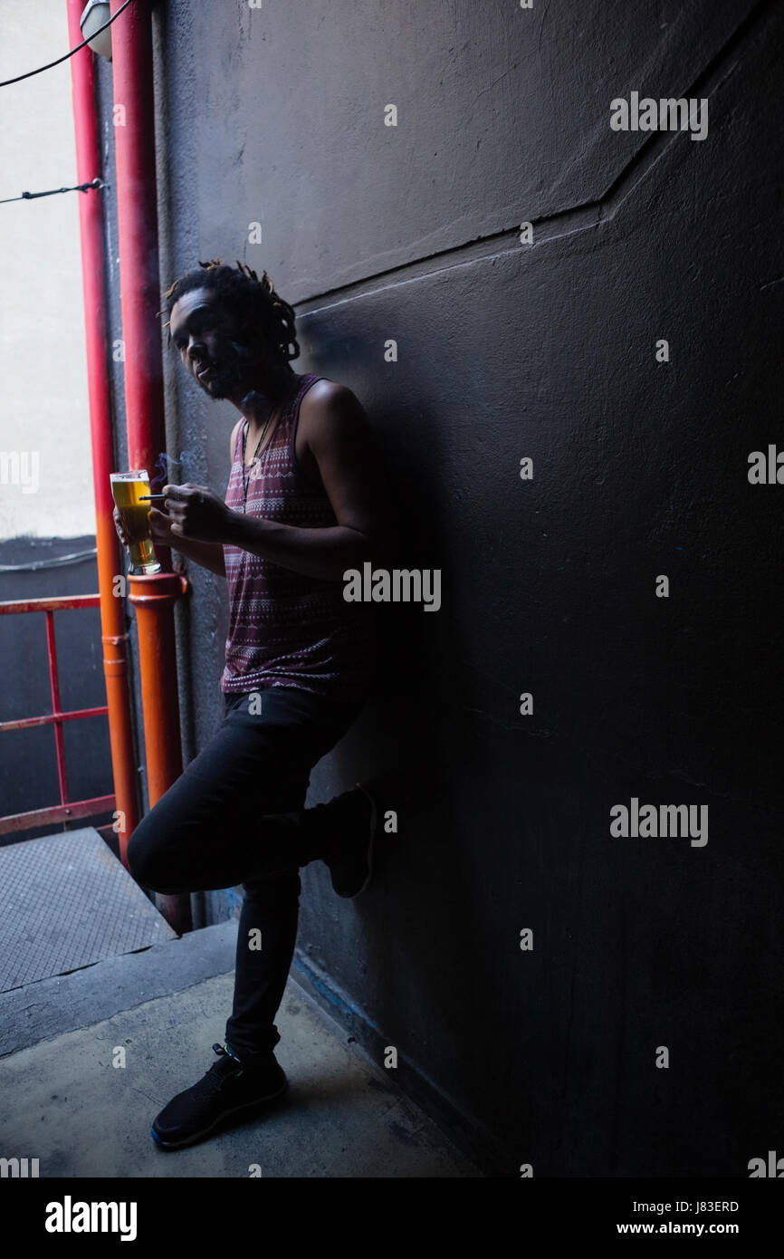 Man smoking while having beer at the entrance of bar Stock Photo - Alamy