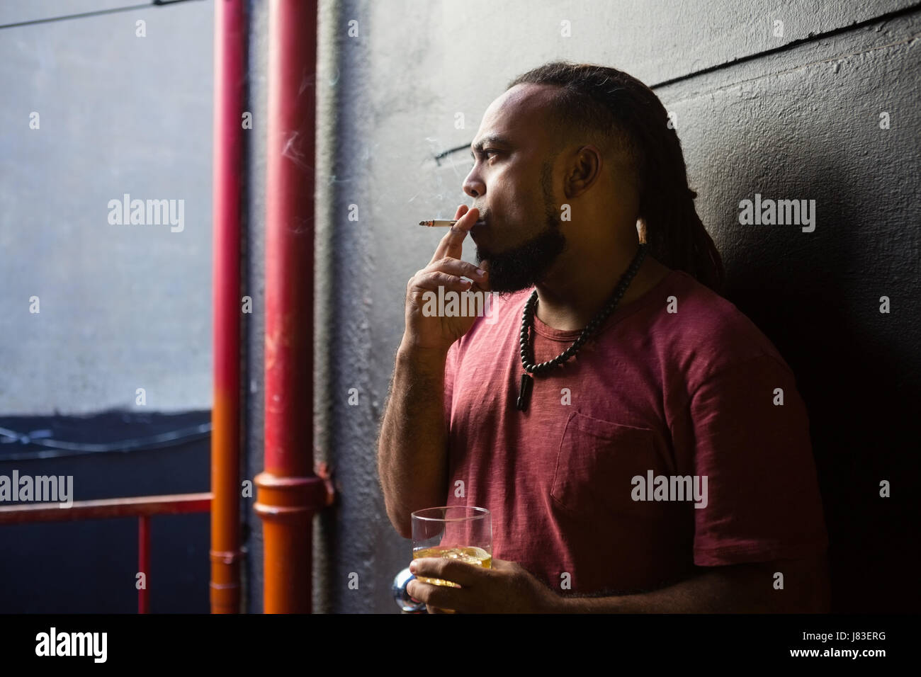 Man smoking while having whisky at the entrance of bar Stock Photo - Alamy