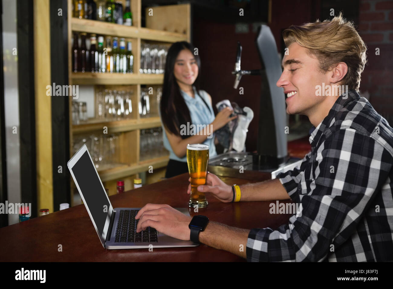 Man having beer while using laptop at bar counter Stock Photo - Alamy