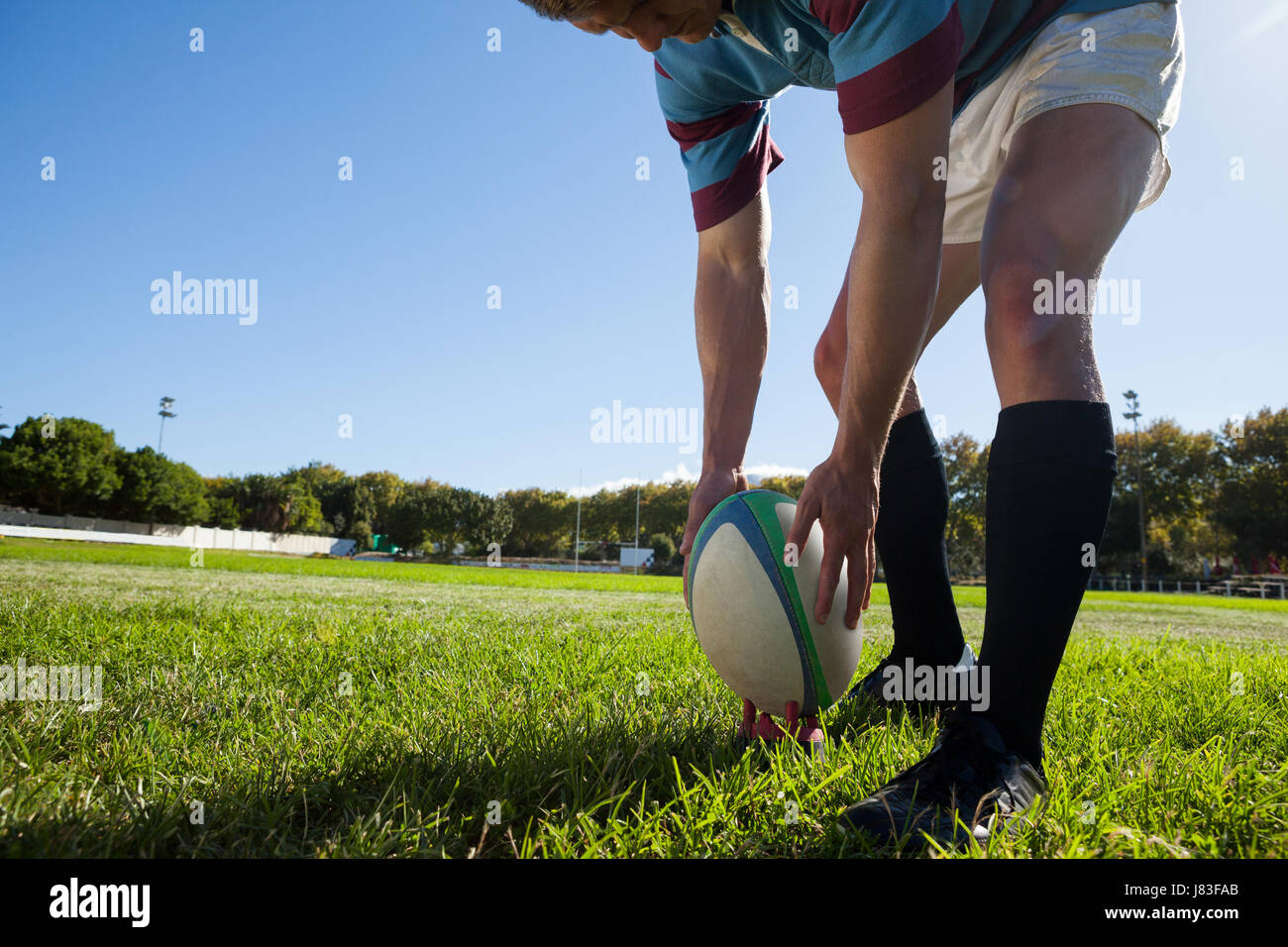 Rugby player getting ready to kick for goal on playing field against ...