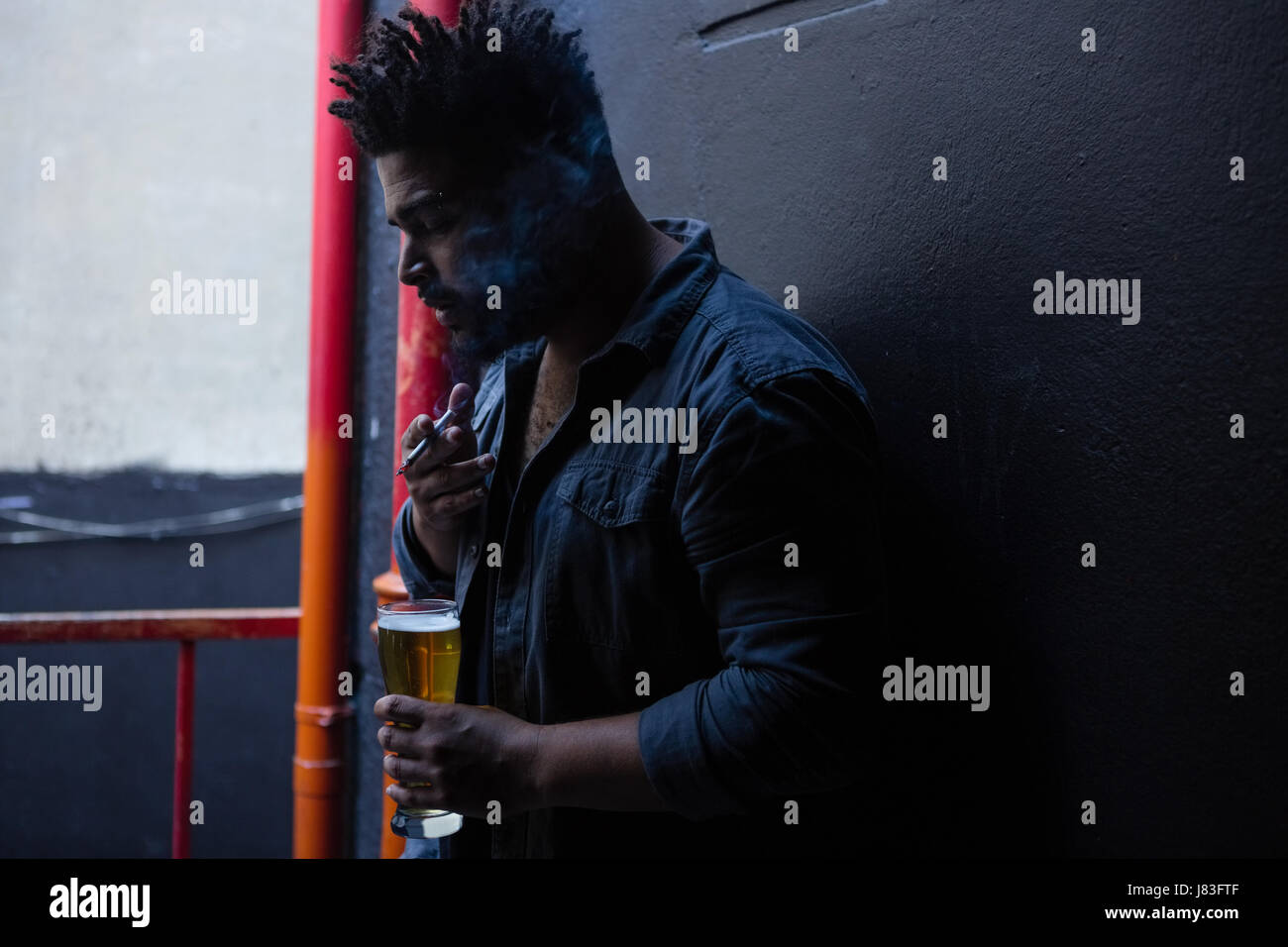 Man smoking while having beer at the entrance of bar Stock Photo - Alamy