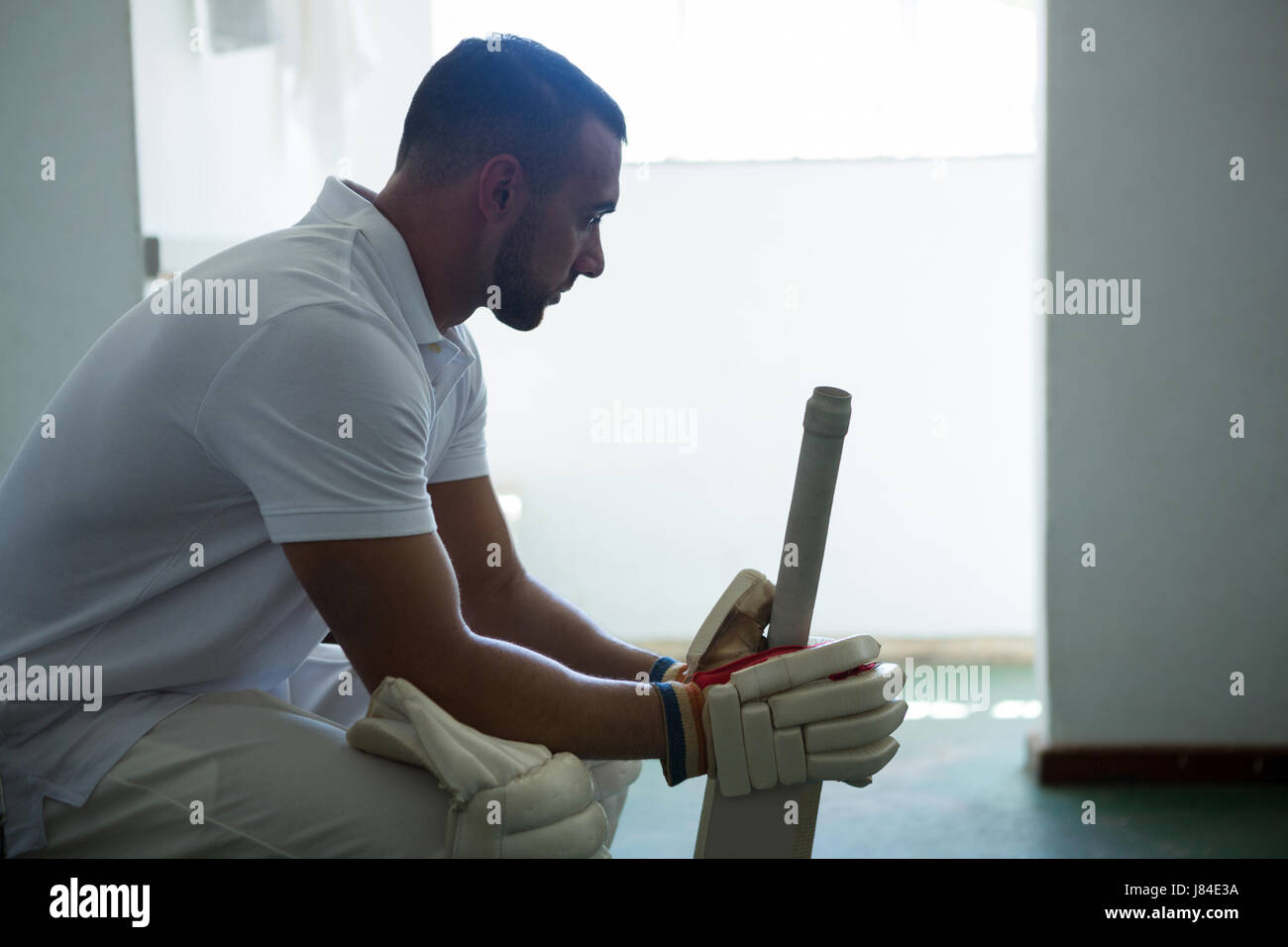 Side view of cricket player sitting on bench at locker room Stock Photo ...