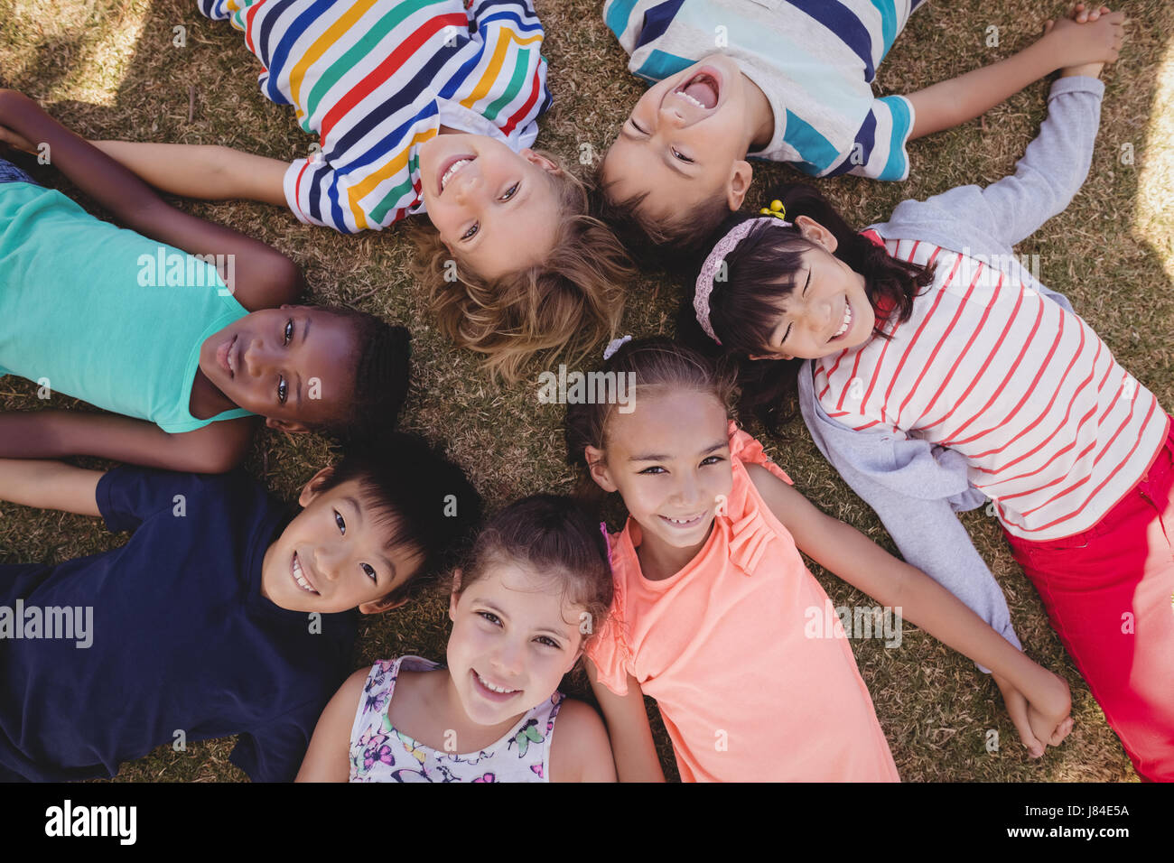 Overhead view of schoolkids lying on grass in park Stock Photo - Alamy