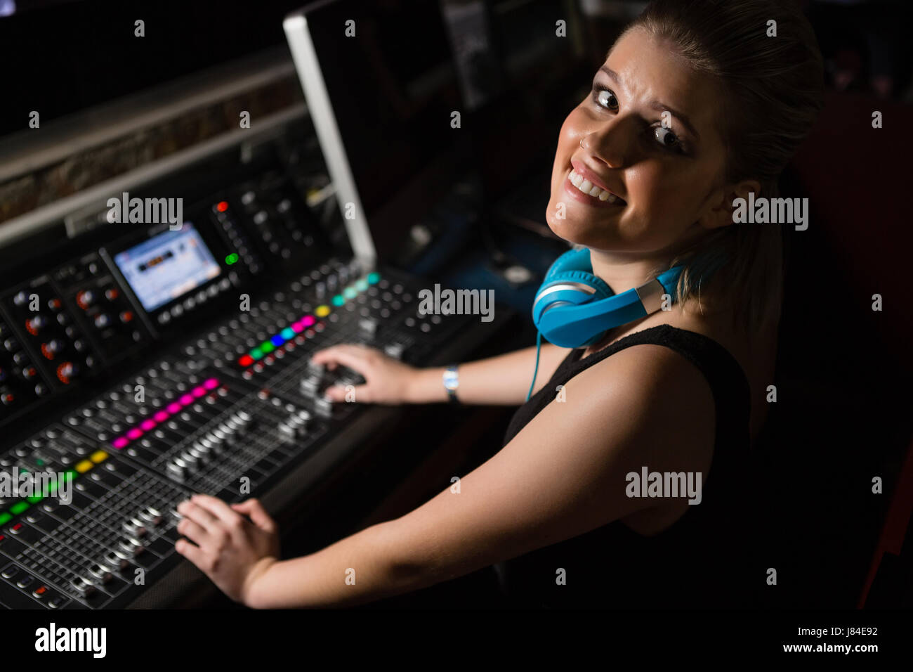Portrait of female audio engineer using sound mixer in recording studio ...