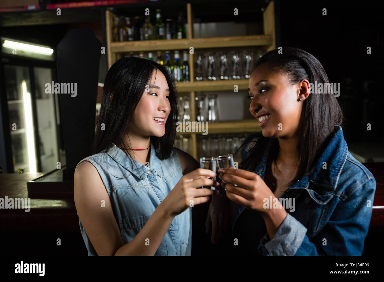 Female friends toasting tequila shot glasses in bar Stock Photo - Alamy