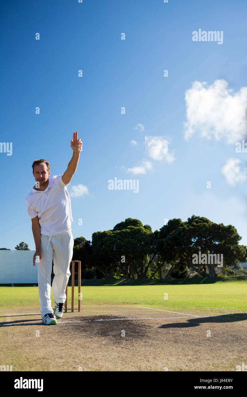 Full length of man bowling while standing on cricket field against sky ...