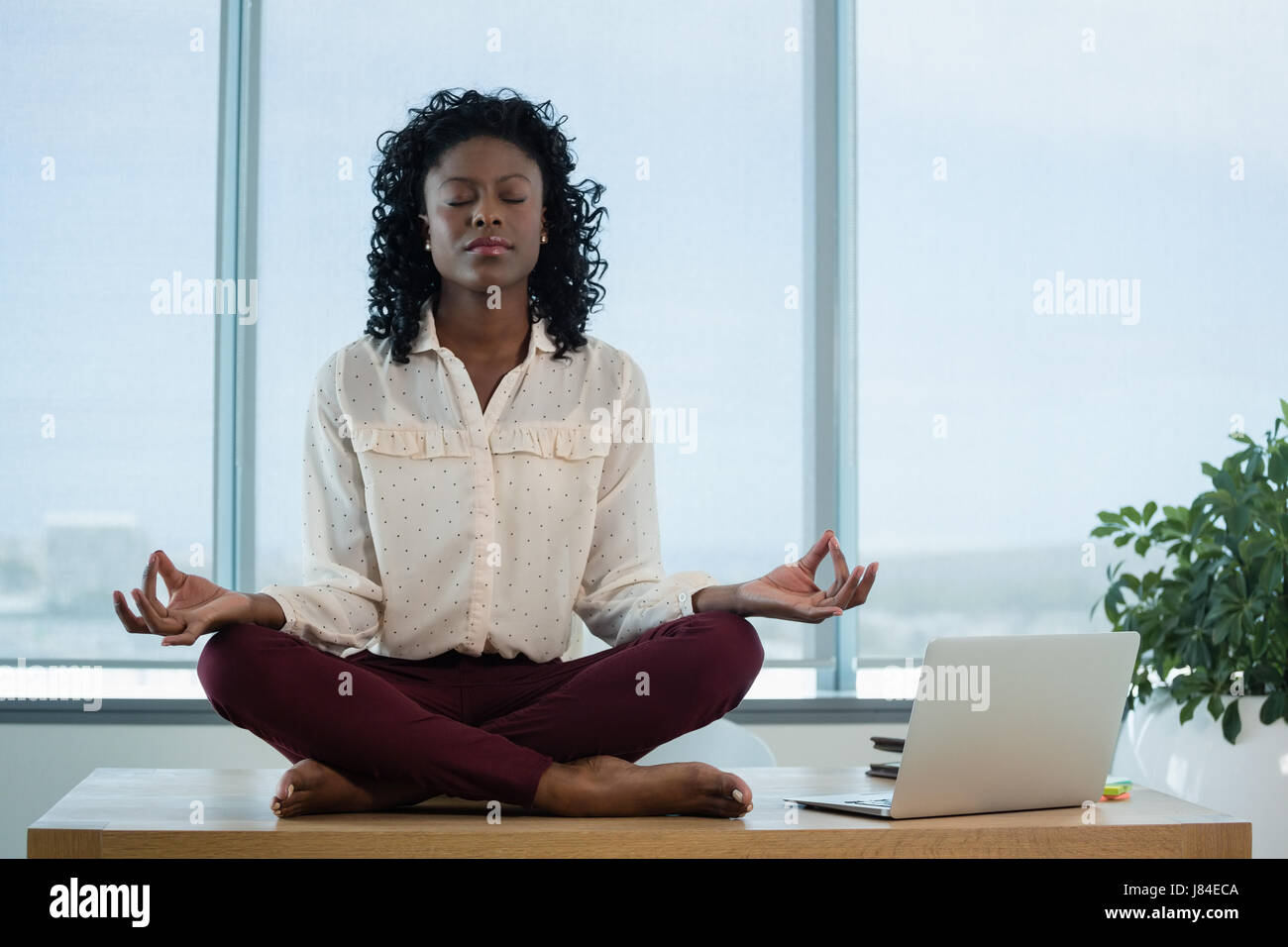 Female executive meditating on desk in office Stock Photo - Alamy