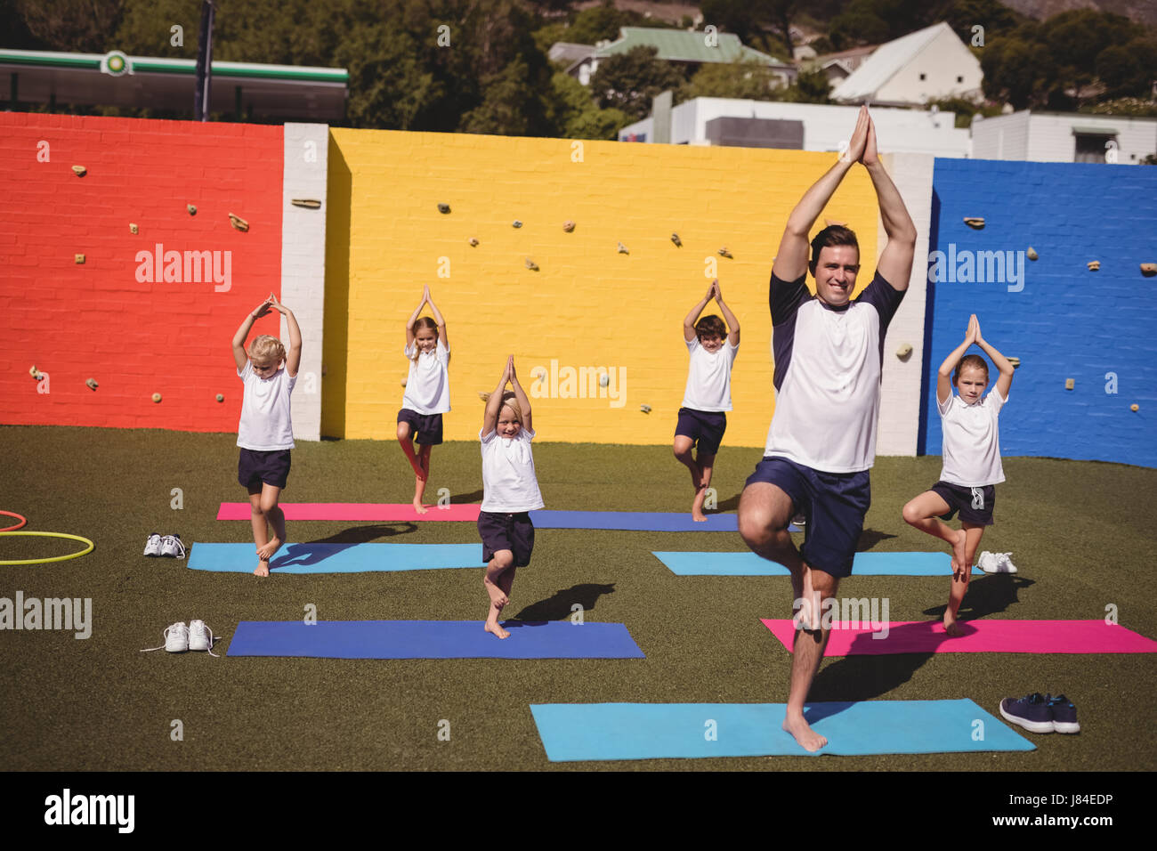 Coach teaching exercise to school kids in schoolyard Stock Photo - Alamy