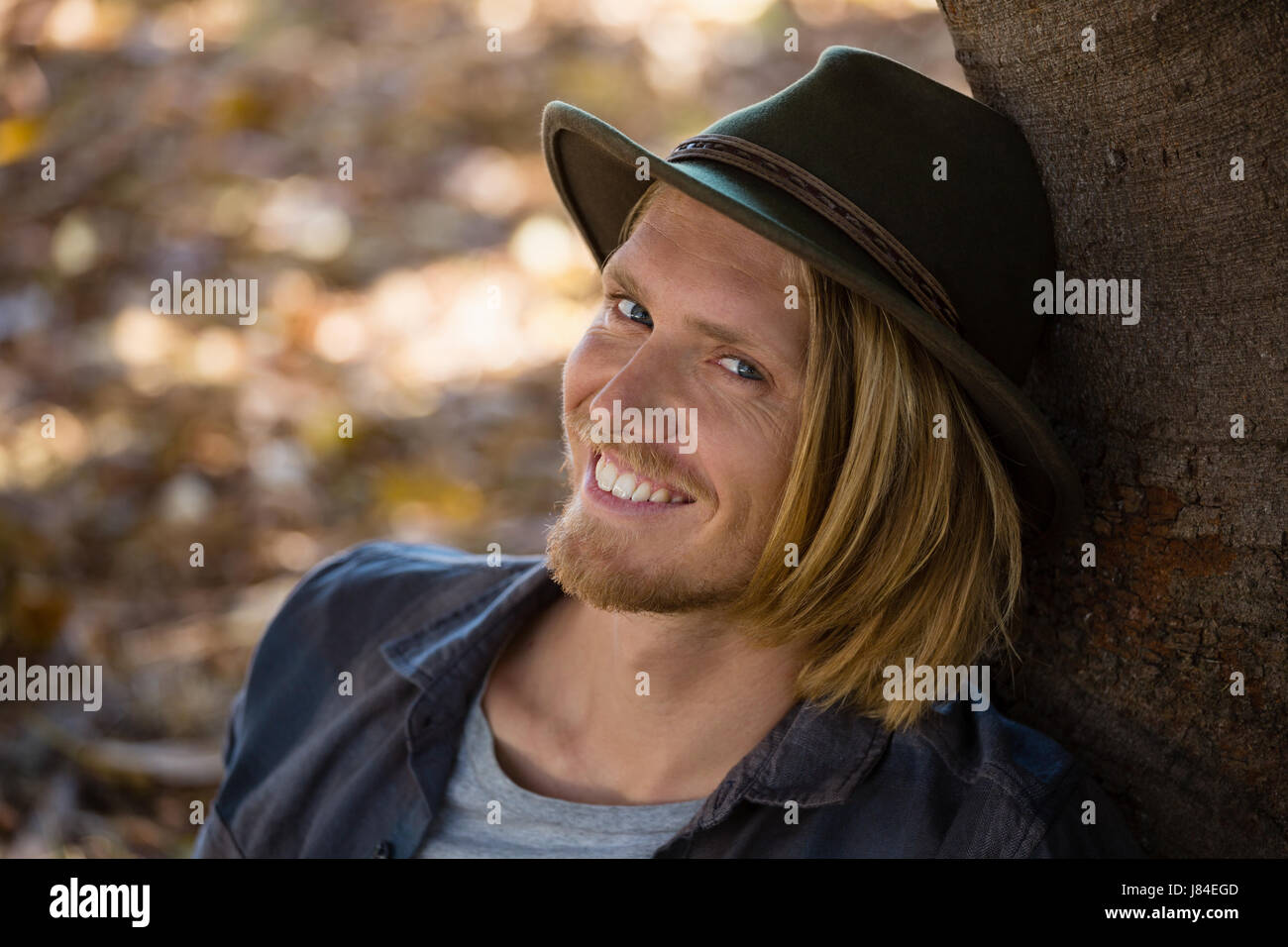 Portrait of man resting against a tree in the park Stock Photo - Alamy