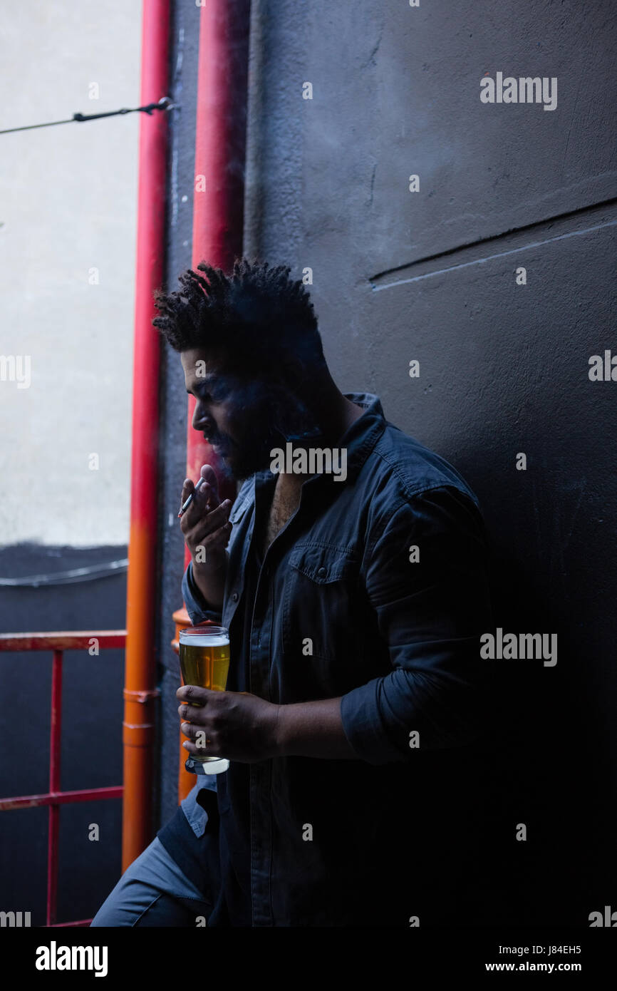 Man smoking while having beer at the entrance of bar Stock Photo - Alamy
