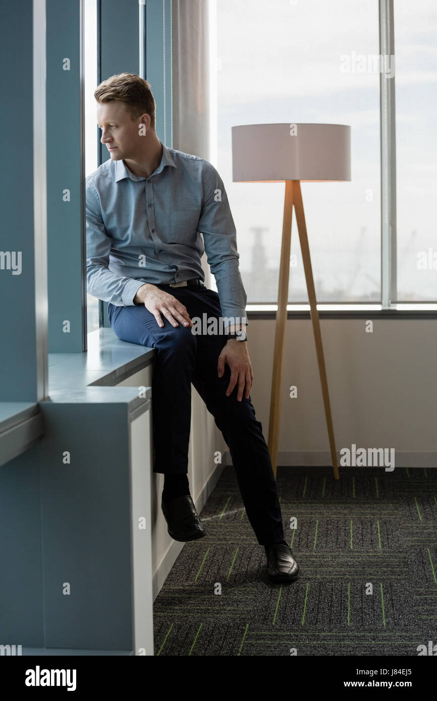Thoughtful executive looking through window in office Stock Photo - Alamy