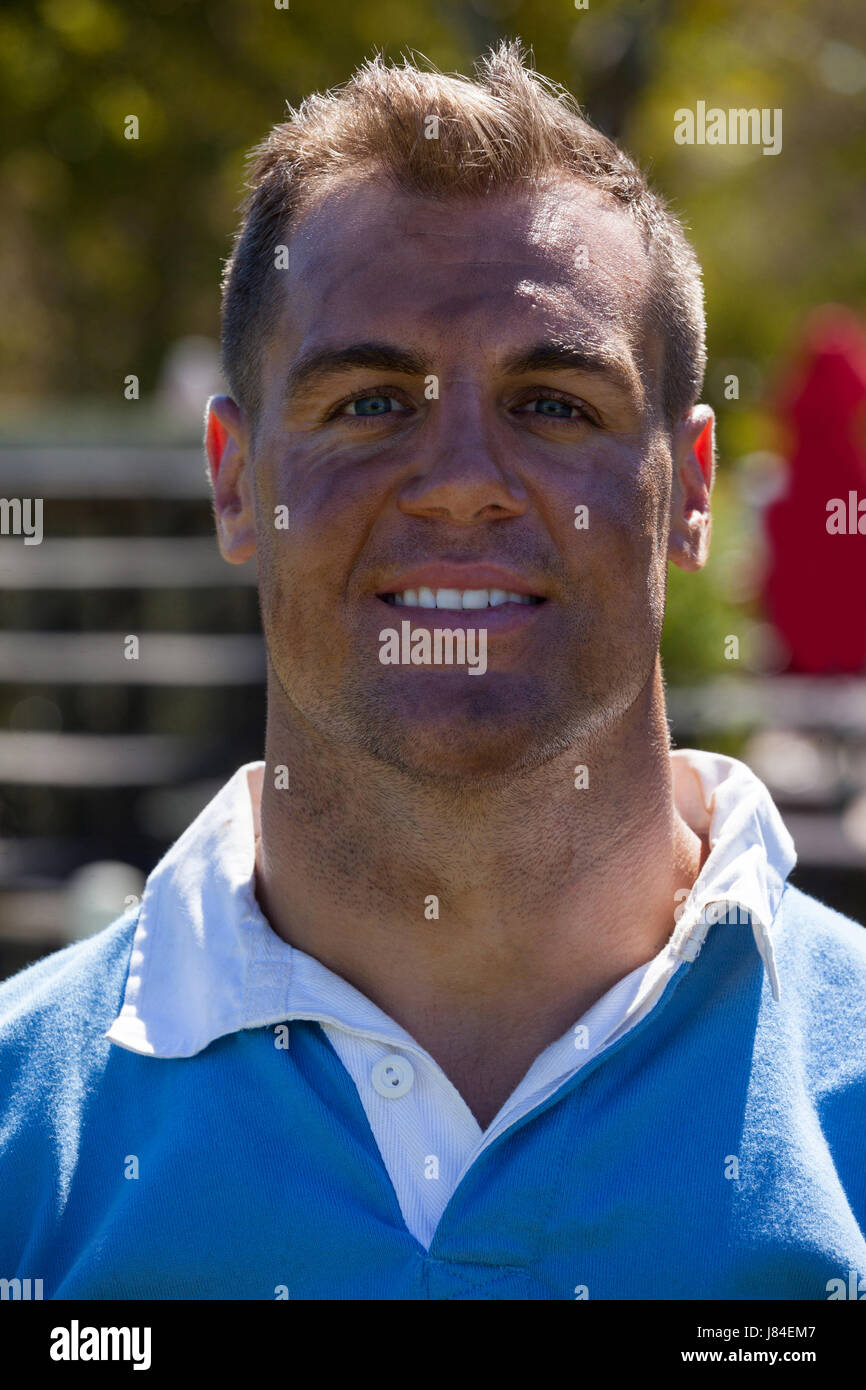 Close up portrait of smiling rugby player at playing field on sunny day ...