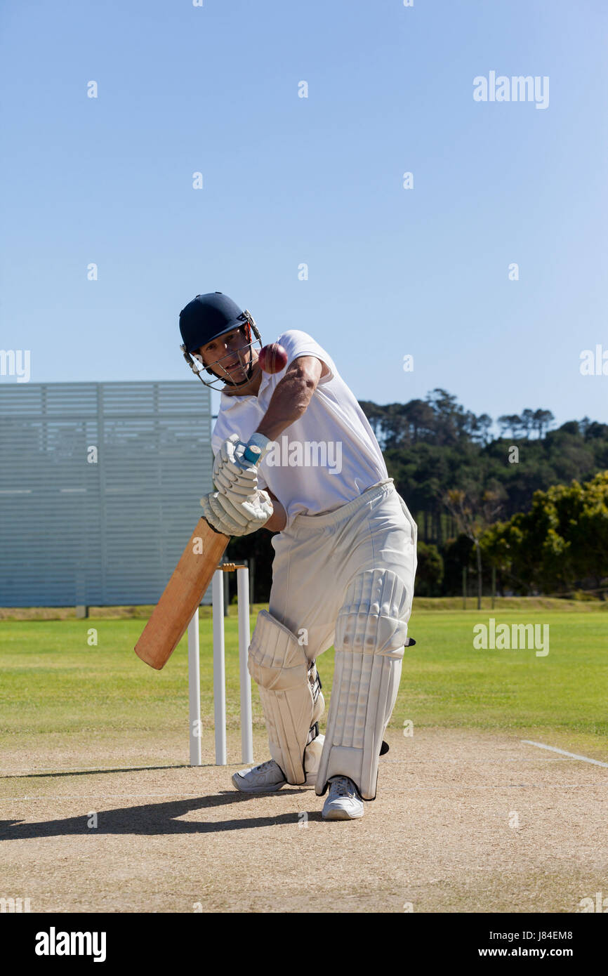 Confident player playing cricket on field against clear blue sky Stock ...