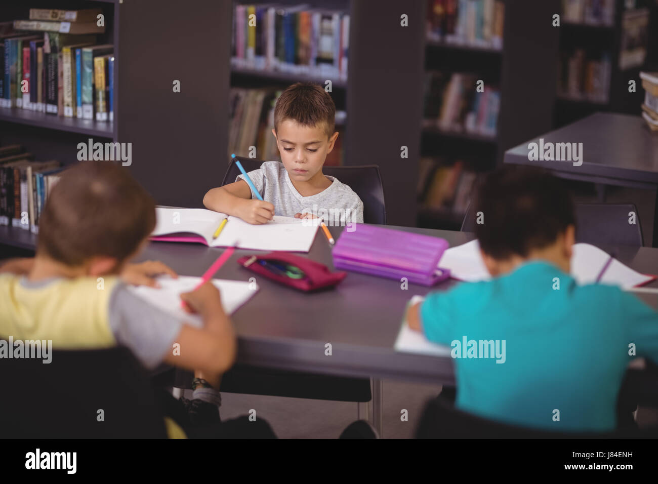 Attentive schoolkids doing their homework in library at school Stock ...