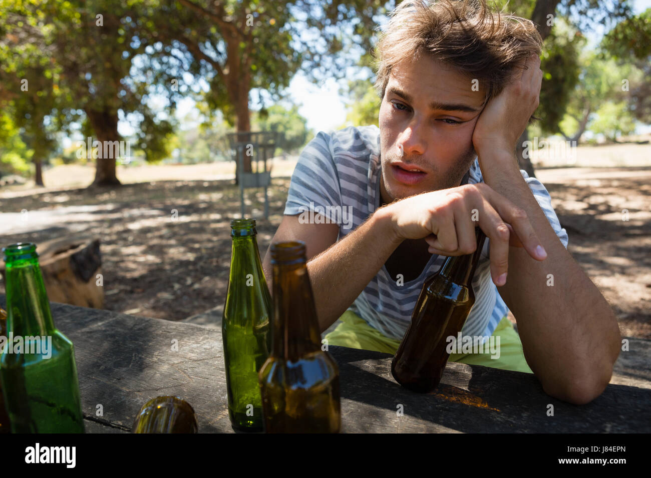 Lonely drunken man holding a beer bottle in the park Stock Photo - Alamy