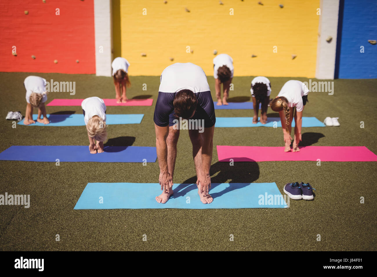 Coach teaching exercise to school kids in schoolyard Stock Photo - Alamy