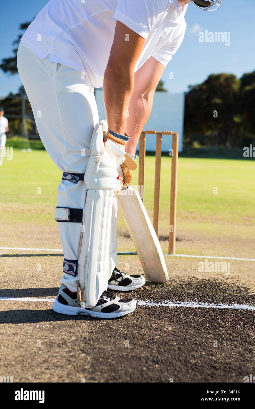 Low section of man playing cricket at sports field on sunny day Stock ...