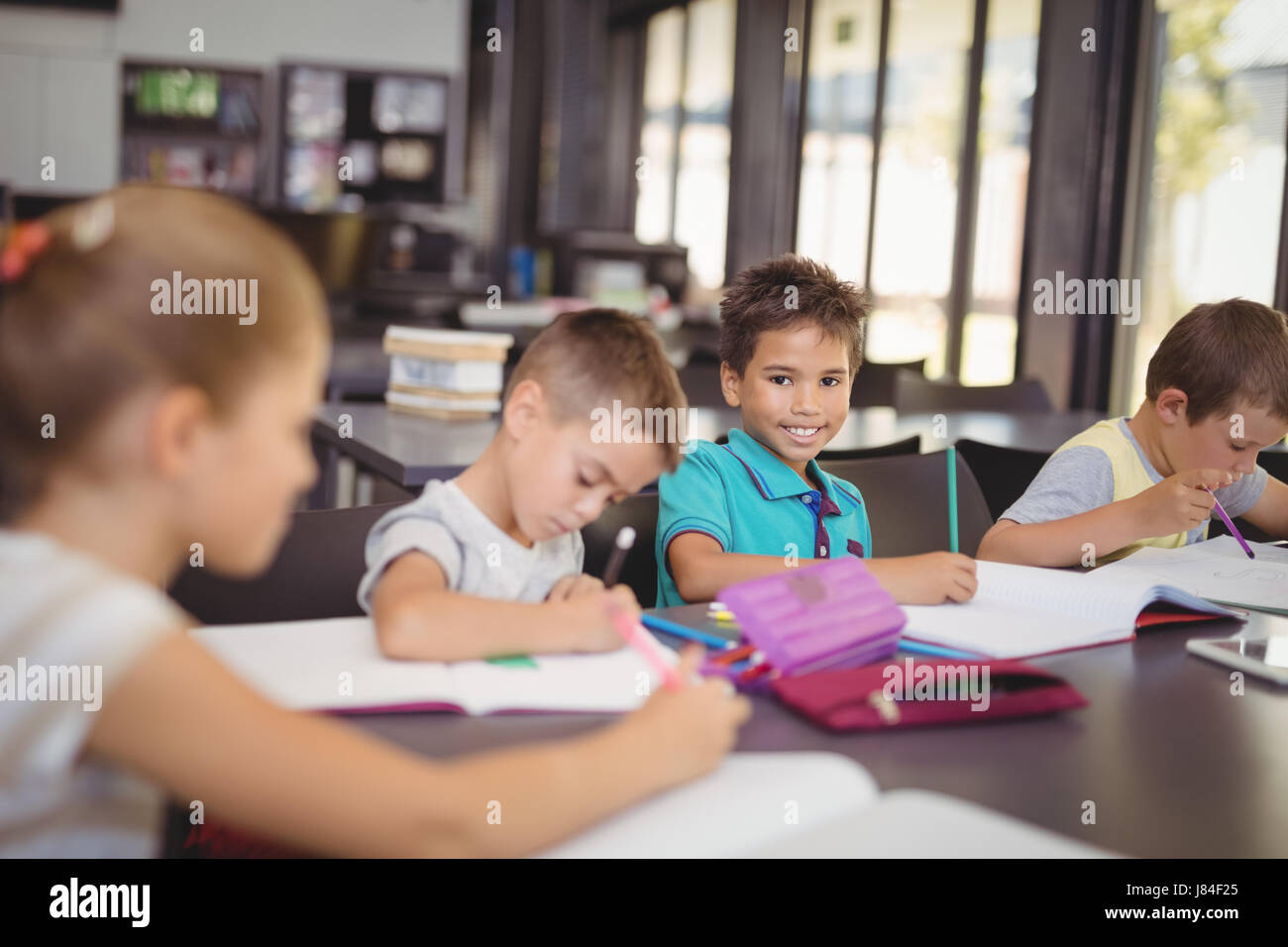 Smiling schoolkids doing their homework in library at school Stock ...
