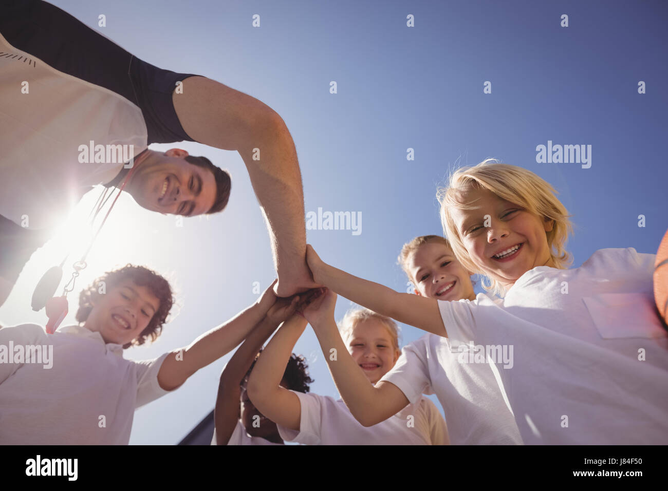 Portrait of happy coach and schoolkids forming handstack in schoolyard Stock Photo - Alamy
