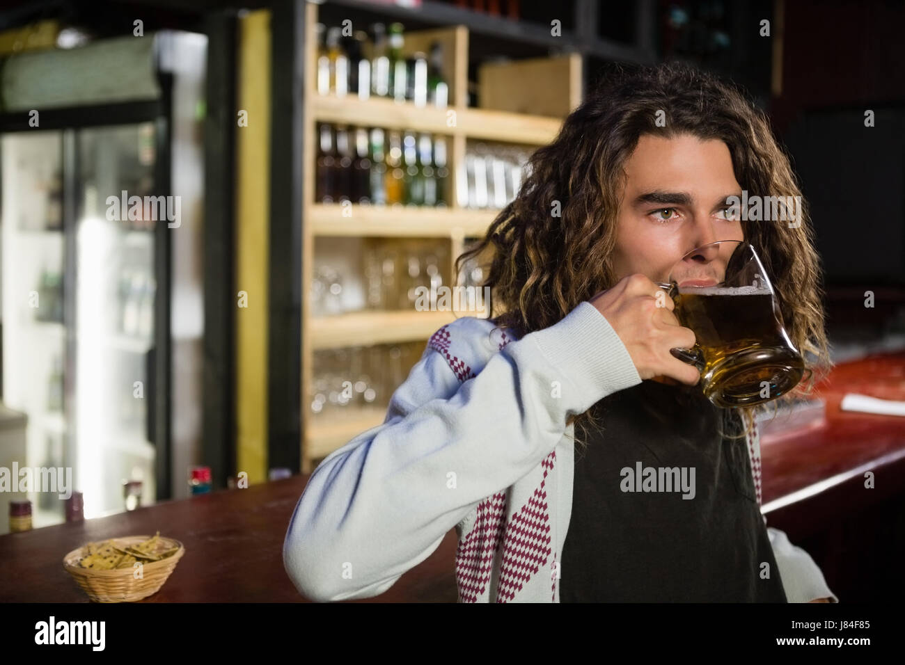 Man having beer while leaning against bar counter Stock Photo - Alamy